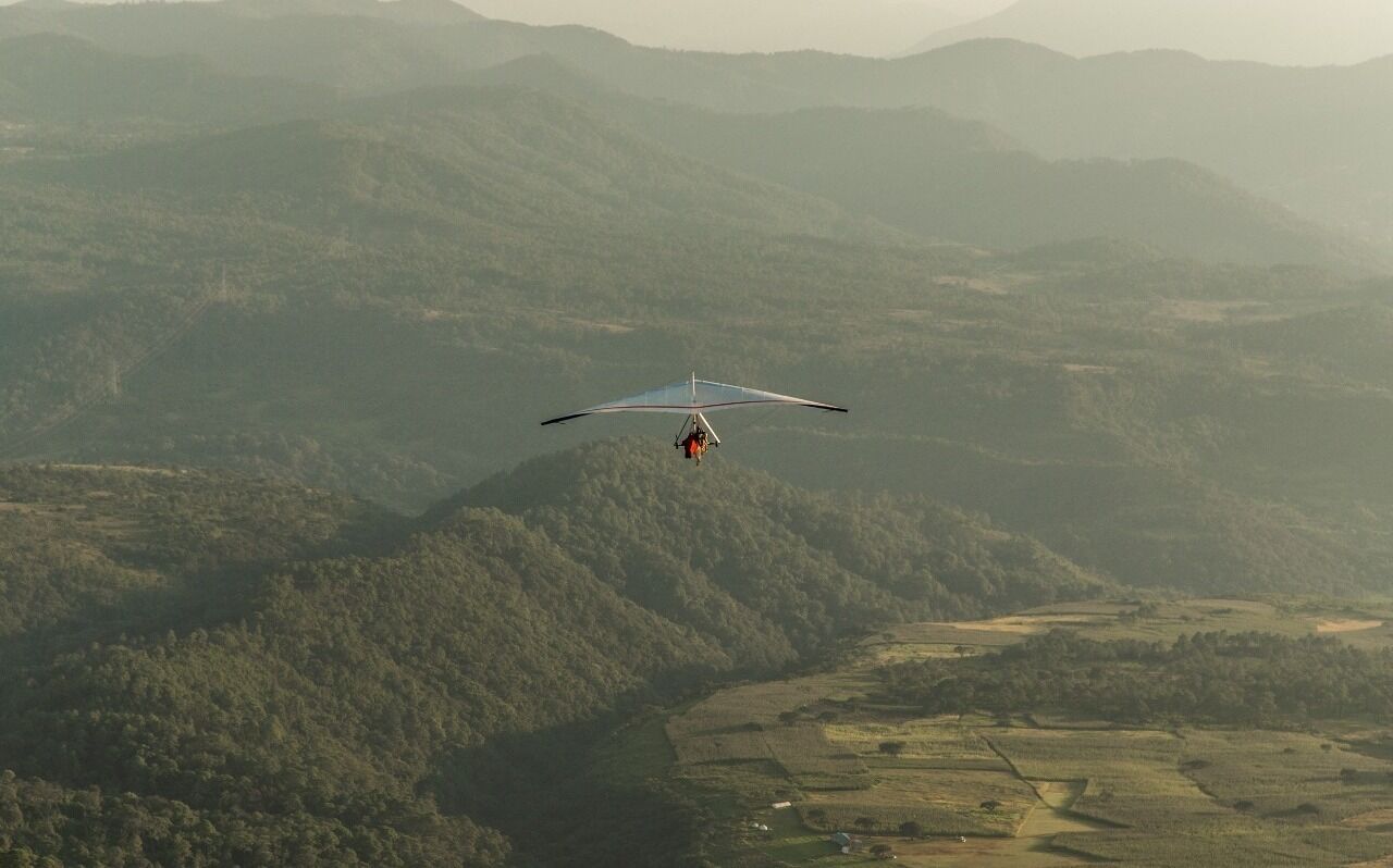 Um planador voando sobre uma paisagem montanhosa.