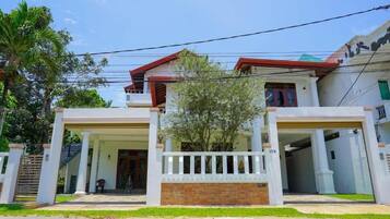 Uma casa de dois andares com varanda coberta e entrada de tijolos.