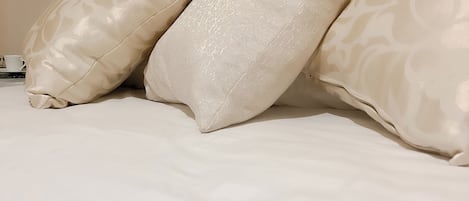 Uma cama com três almofadas e cabeceira.
