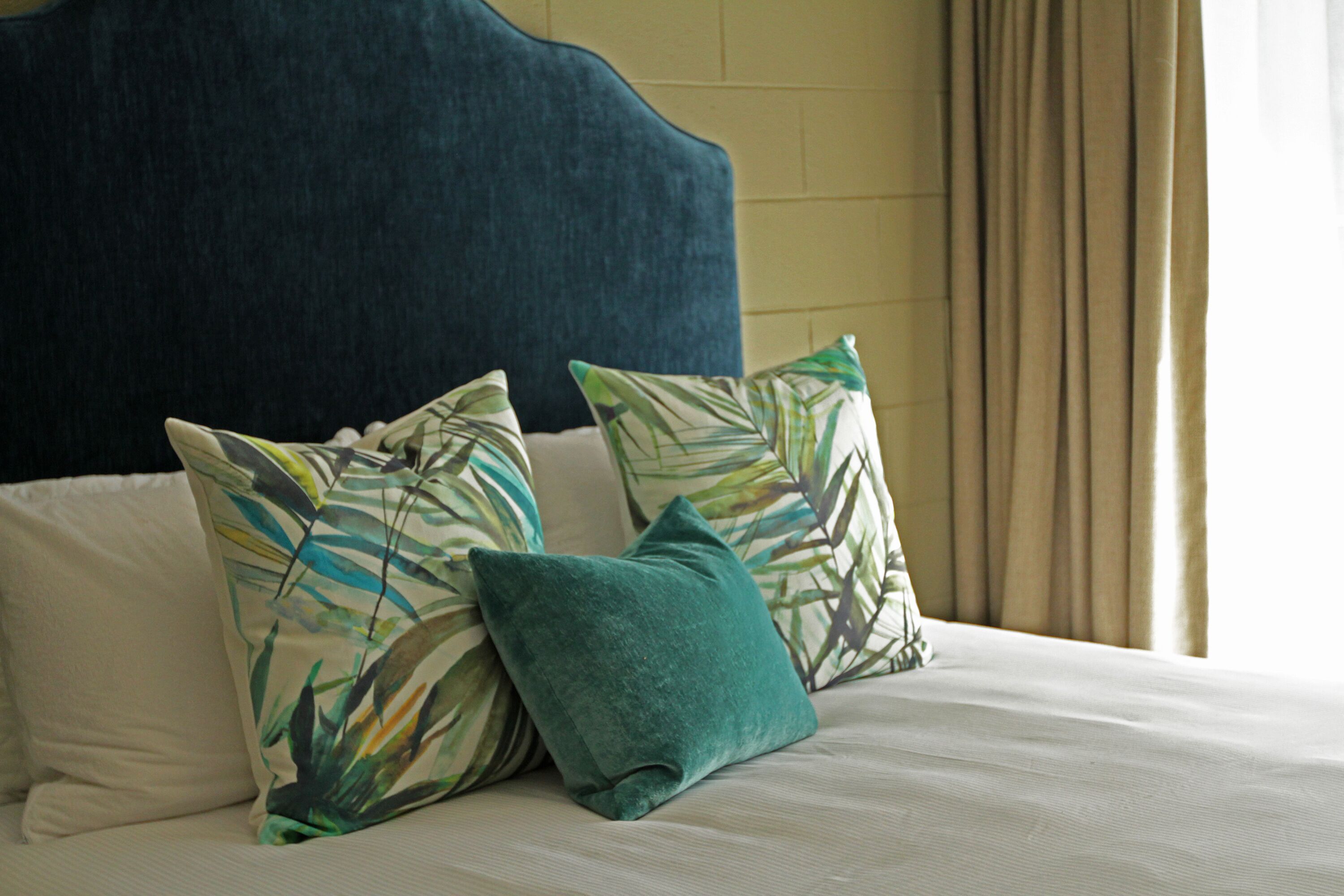 Cama com duas almofadas decorativas e cabeceira escura.