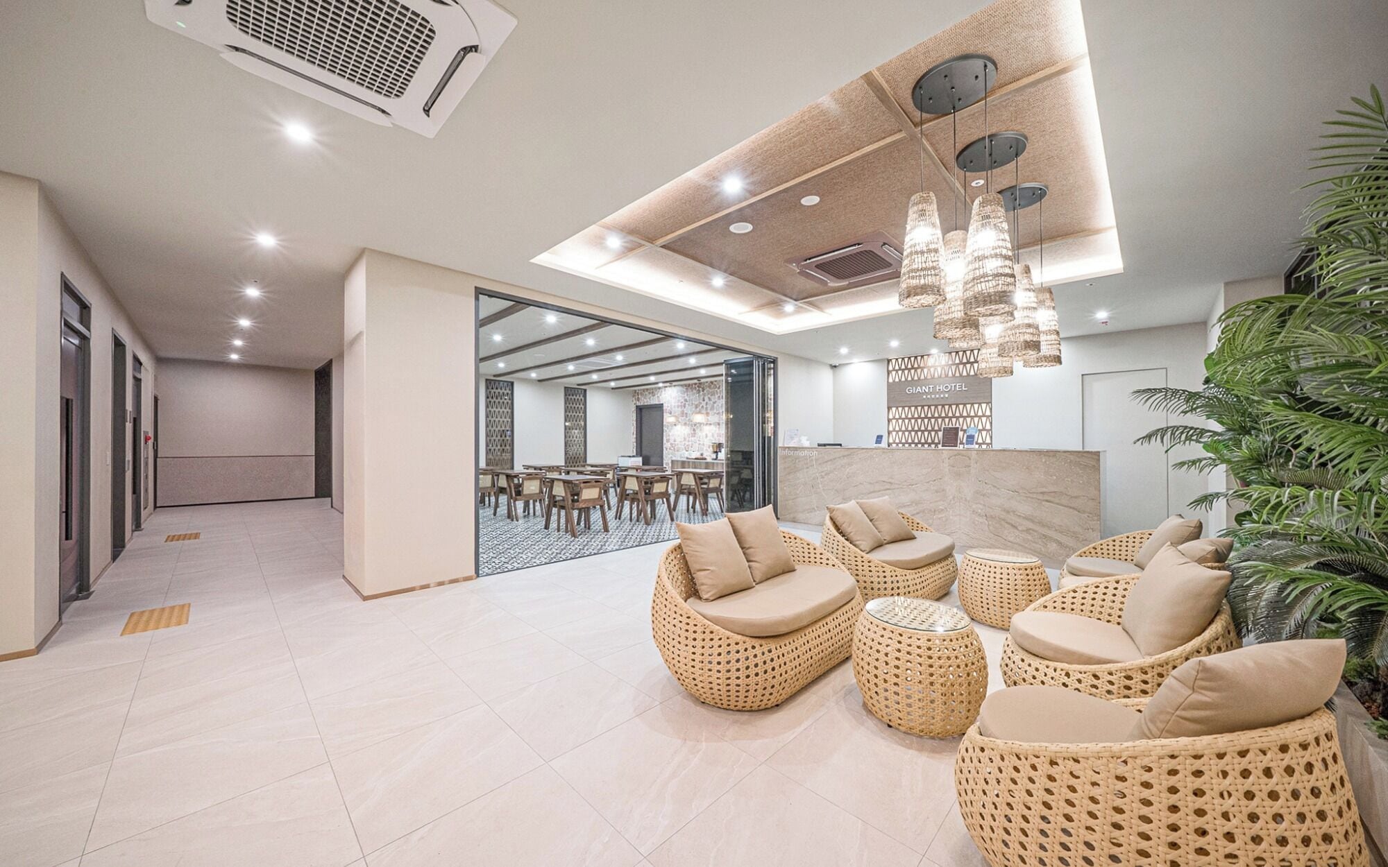 Um saguão de hotel com móveis de vime, um balcão de recepção e vista para uma área de refeições.