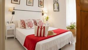 Um quarto bem arrumado, com cama, mesas de cabeceira e uma mesinha de apoio.