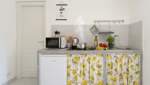 Uma cozinha compacta com micro-ondas, torradeira, chaleira e uma pequena geladeira.