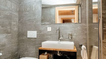 Casa de banho moderna com sanita, lavatório e cabine de duche em vidro.