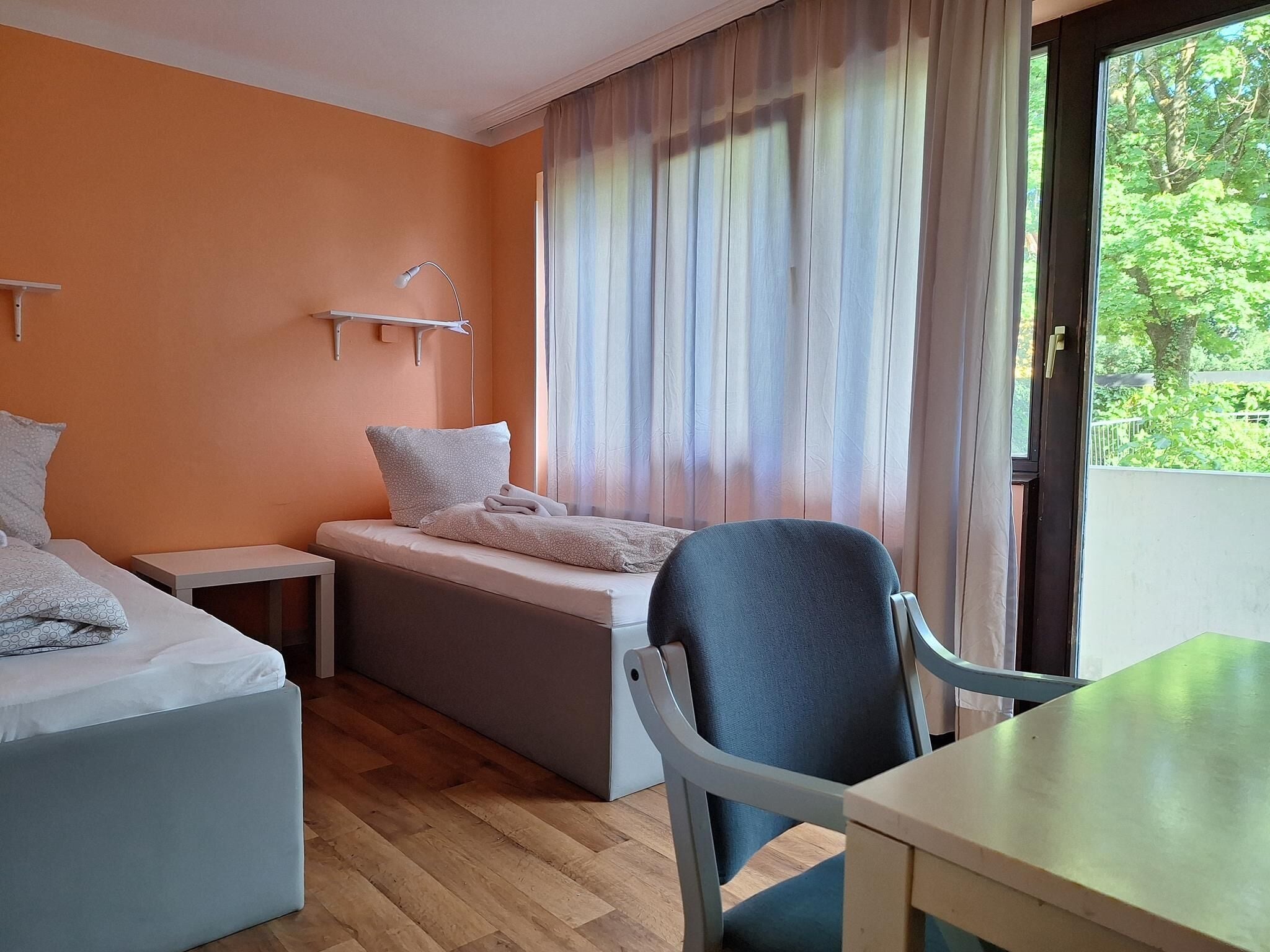 Quarto moderno com cama, mesa de cabeceira e uma cadeira.