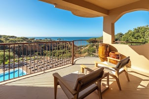 Uma varanda com vista para a piscina, mobiliário de madeira e vista do oceano.