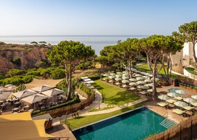 Área da piscina com guarda-sóis, espreguiçadeiras e vista para o oceano.