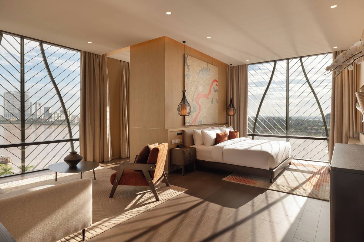 Quarto de hotel moderno com uma cama grande, uma mesa e uma cadeira. Há uma janela ampla com vista para a cidade.