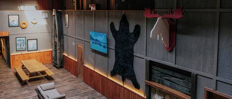 Decoração moderna com lareira, bancos de madeira e obras de arte nas paredes.