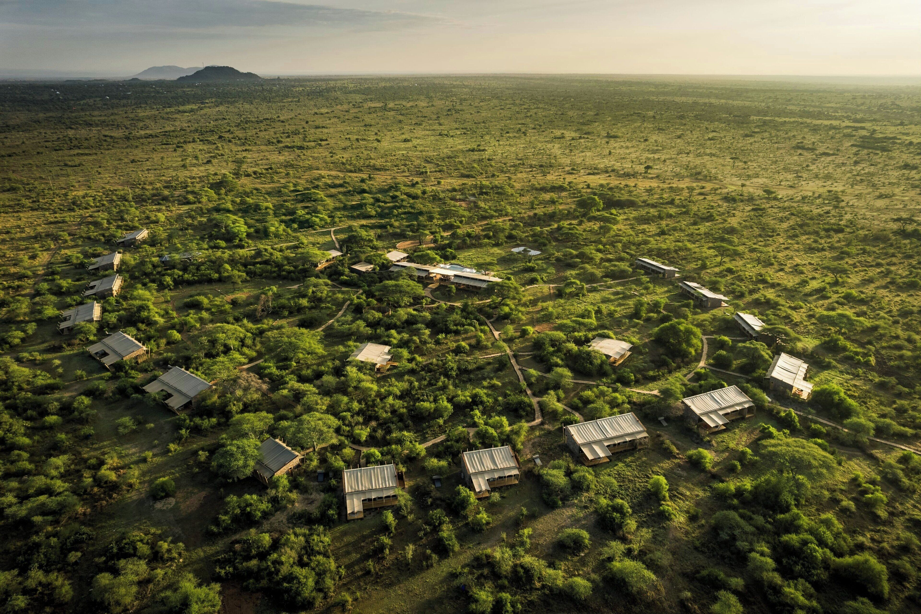 Vista aérea de uma área rural com vários edifícios pequenos rodeados por vegetação densa.