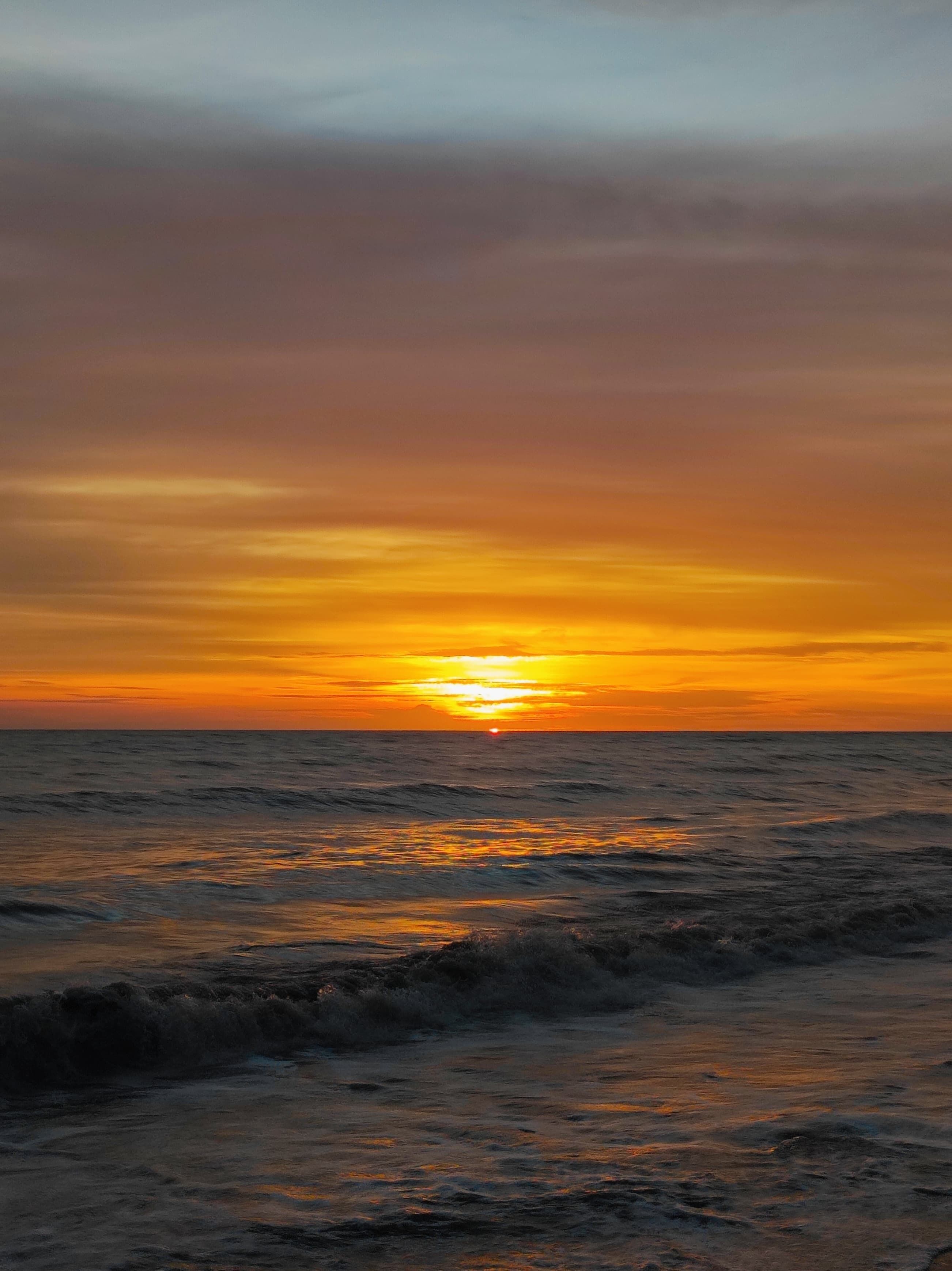 Um pôr do sol sobre o oceano com ondas.