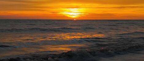 Um pôr do sol sobre o oceano com ondas.