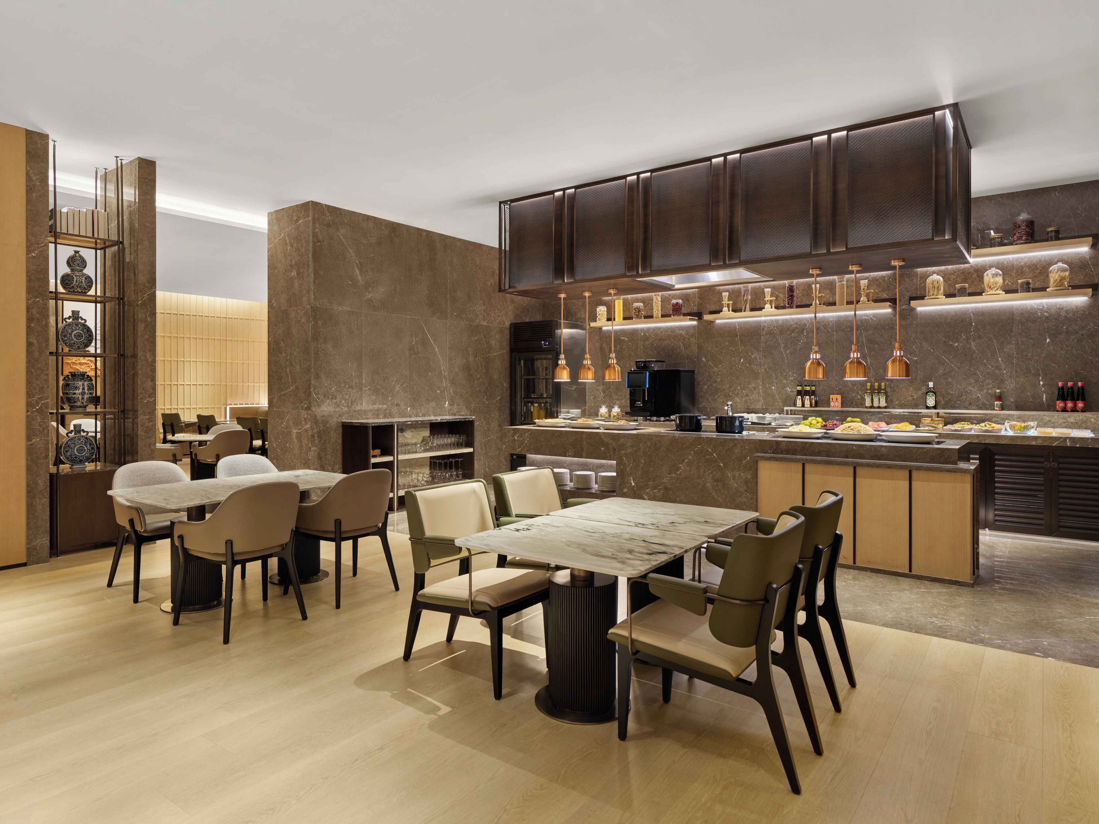 Uma zona de refeições moderna com uma mesa e cadeiras de mármore, uma cozinha com bancada de mármore e uma exposição de objetos decorativos em prateleiras.
