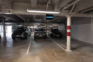 Um parque de estacionamento com vários níveis e carros estacionados em lugares marcados.