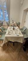 Uma sala de jantar com uma grande mesa posta para quatro pessoas, cercada por quatro cadeiras verdes.