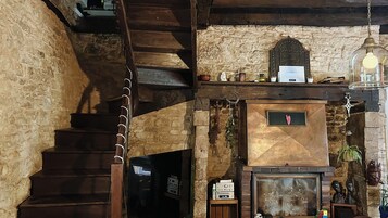 Um interior rústico com parede de pedra, escada de madeira e lareira com uma placa decorativa.