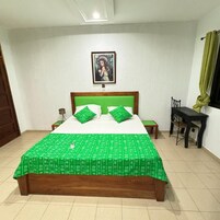 Quarto com cama, mesa de cabeceira, escrivaninha e uma cadeira.