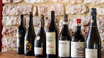 Várias garrafas de vinho dispostas numa superfície de madeira, com um muro de pedra ao fundo.