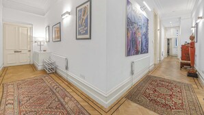Um corredor com paredes brancas, obras de arte emolduradas e tapetes estampados.