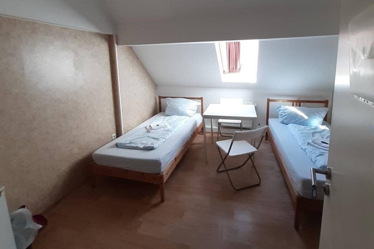 Acomodação pequena, com um quarto e duas camas, uma escrivaninha e uma cadeira.