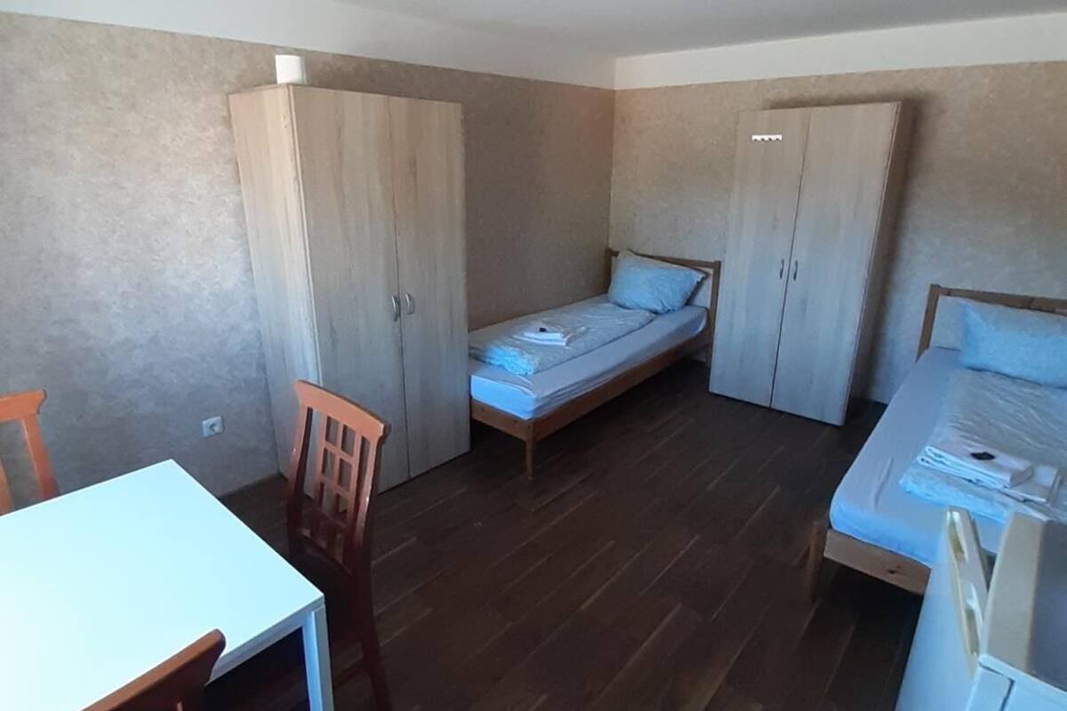 Quarto compacto com uma cama, escrivaninha e armário.