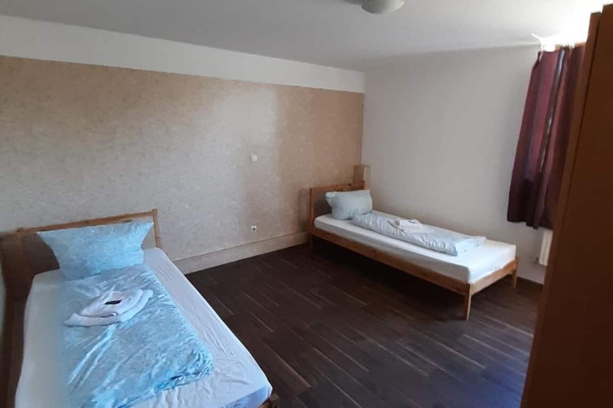 Quarto com duas camas, piso de madeira e luminária no teto.