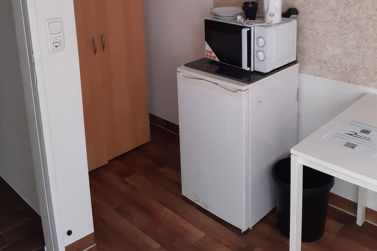 Uma cozinha compacta equipada com micro-ondas, mini-geladeira e uma mesa.