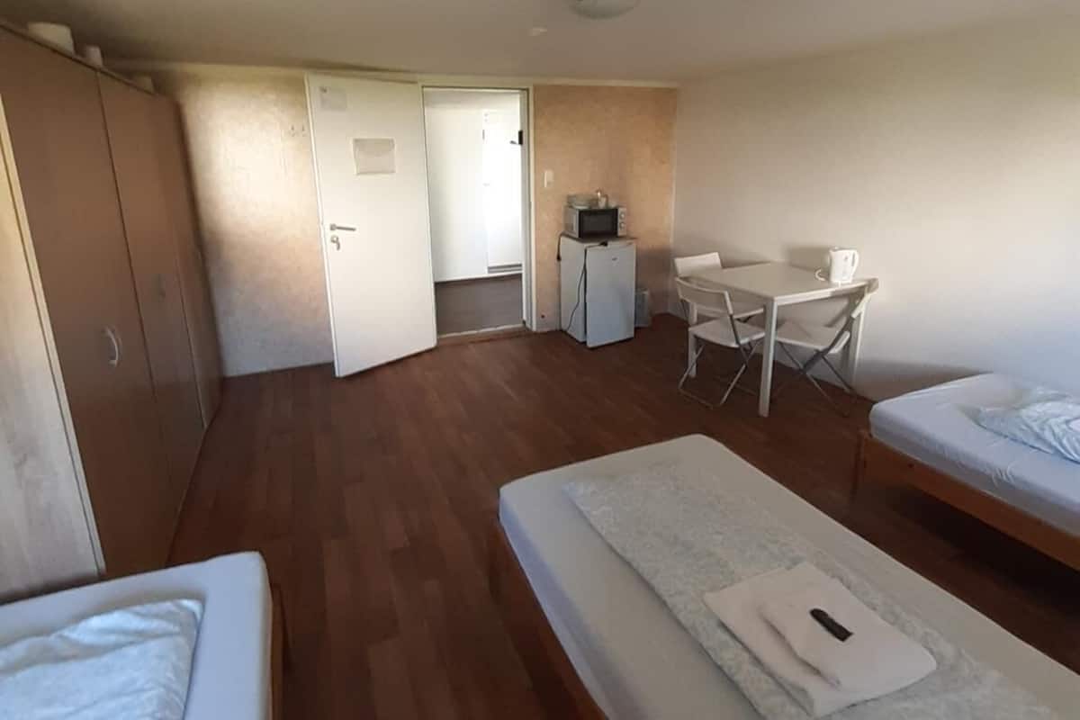 Quarto compacto com uma cama, escrivaninha e cozinha compacta.