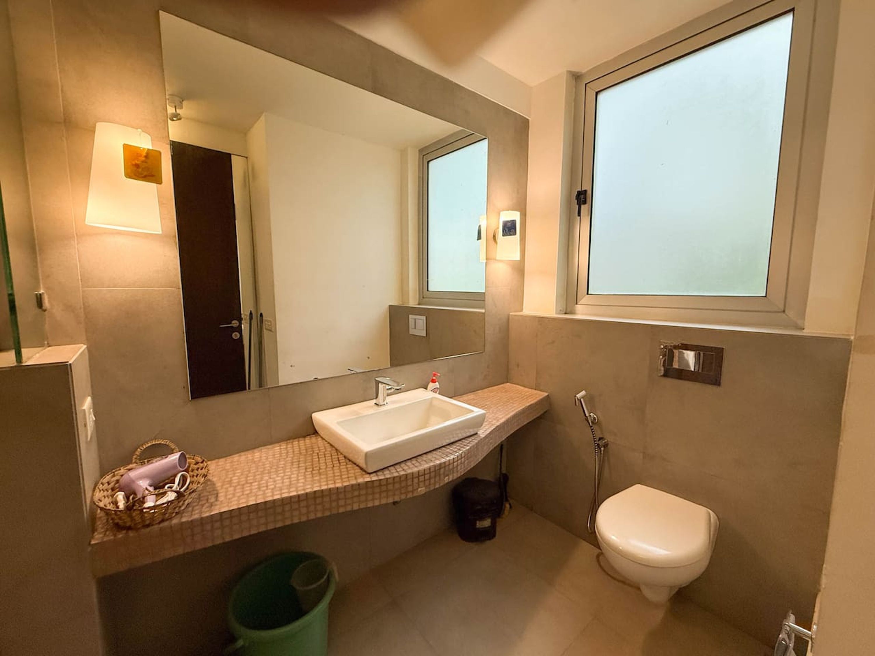 Uma casa de banho moderna com um espelho grande, uma sanita, uma pia e um chuveiro.