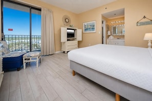 Quarto de hotel com varanda, cama, televisão, cômoda e banheiro.