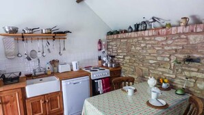 Uma cozinha com armários de madeira, uma máquina de lavar louça, um fogão e uma mesa posta com toalha.