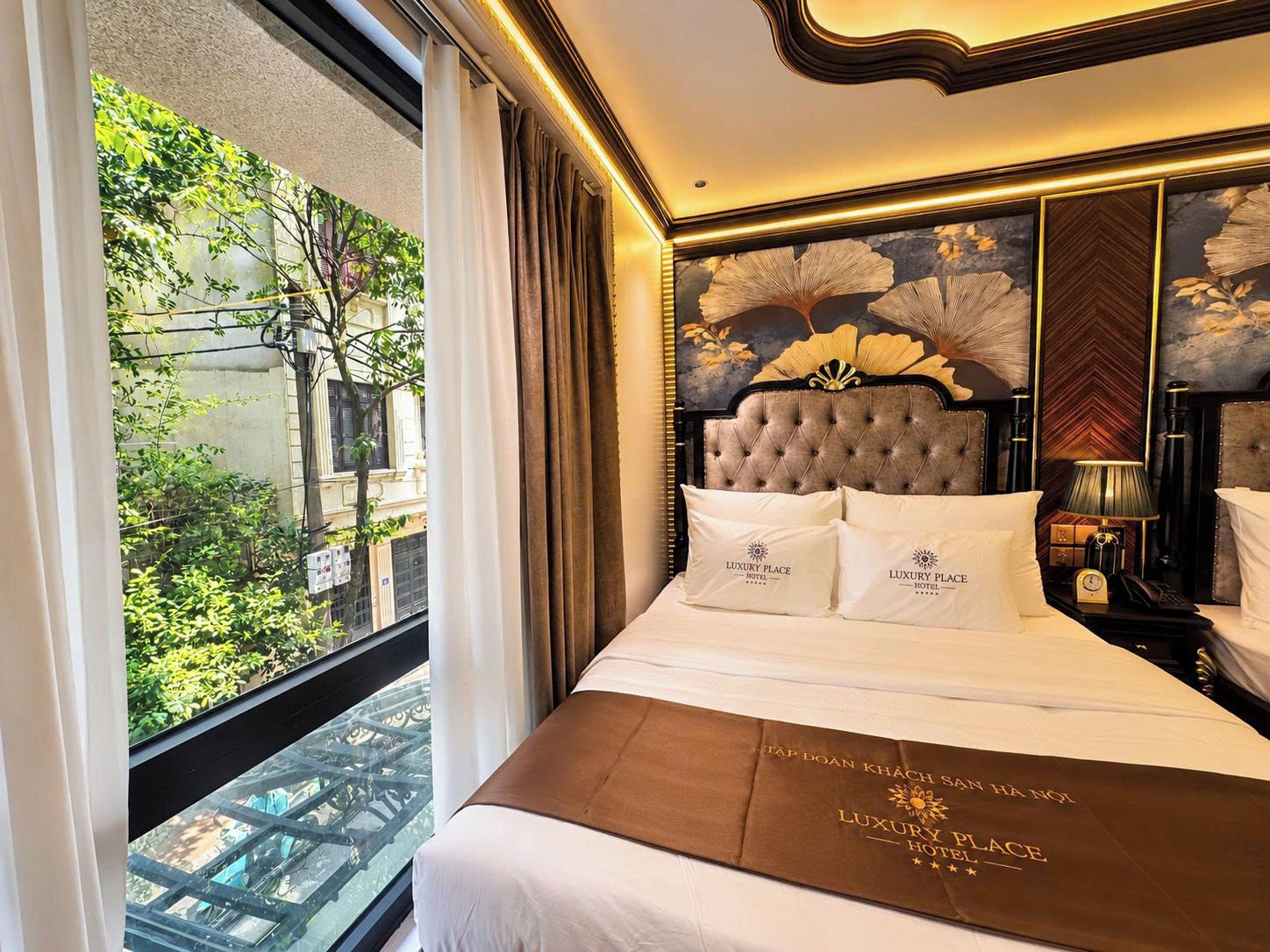 Quarto de hotel com uma cama grande, vista para o verde lá fora e uma parede decorativa.