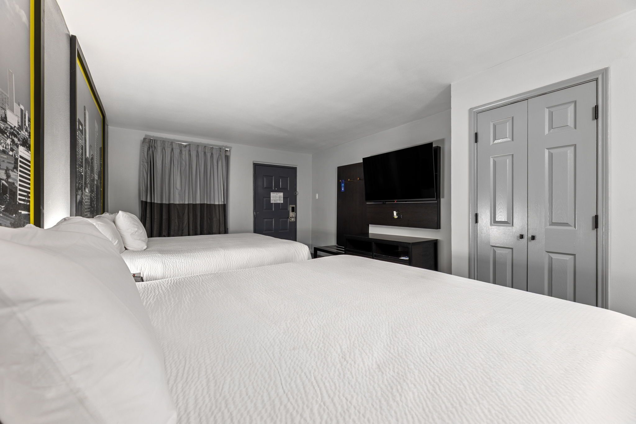 Quarto de hotel com duas camas, televisão de tela plana, escrivaninha e armário.
