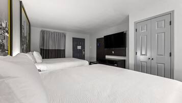 Quarto de hotel com duas camas, televisão de tela plana, escrivaninha e armário.