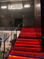 Uma escadaria com iluminação vermelha leva à entrada de um edifício com a placa 'EL DORADO CASINO'.