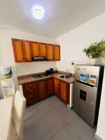 Cozinha compacta com armários de madeira, geladeira de aço inoxidável e bancada com pia.