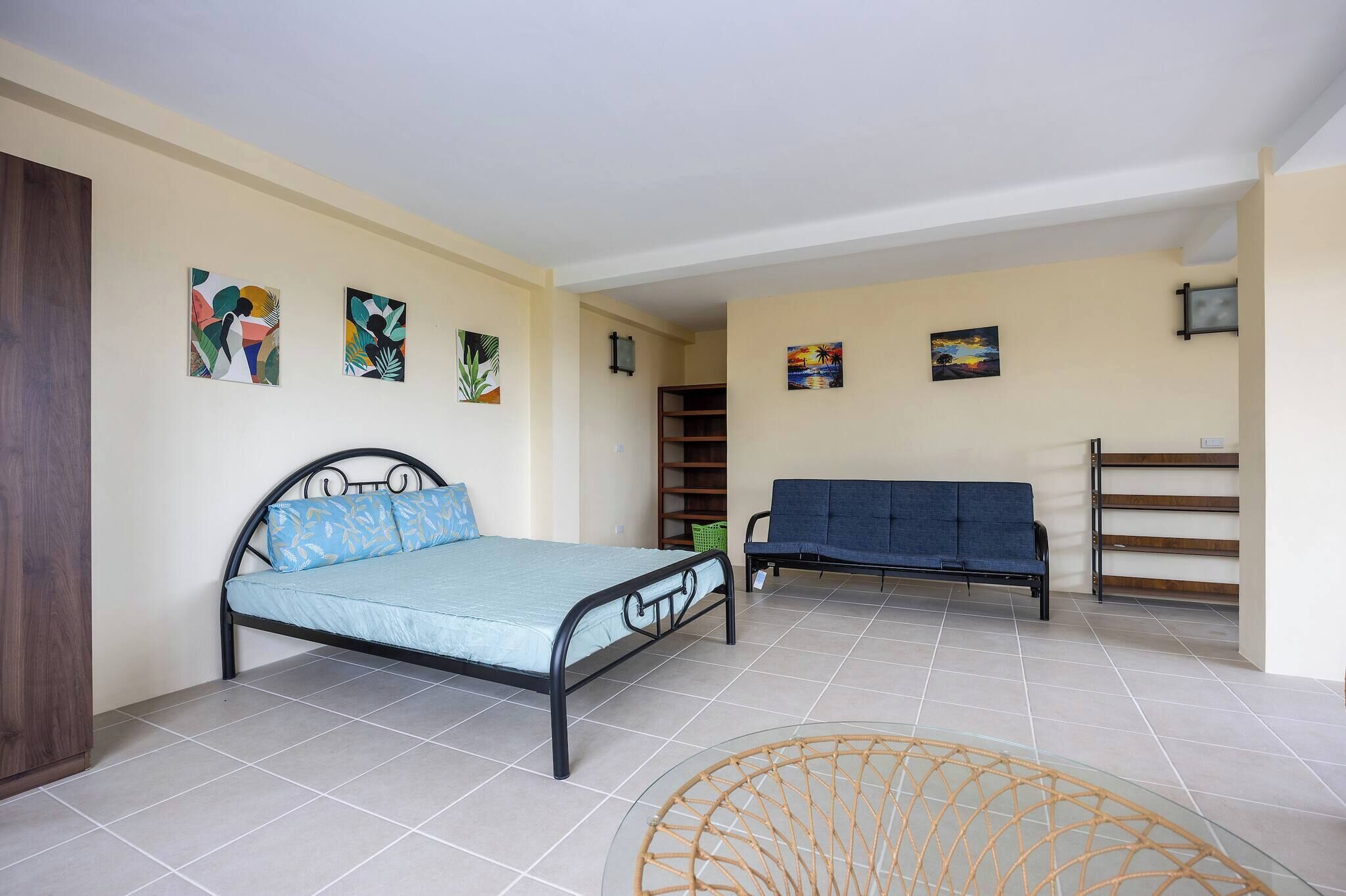 Quarto com cama, sofá e obras de arte nas paredes.
