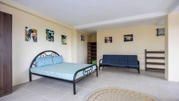 Quarto com cama, sofá e obras de arte nas paredes.