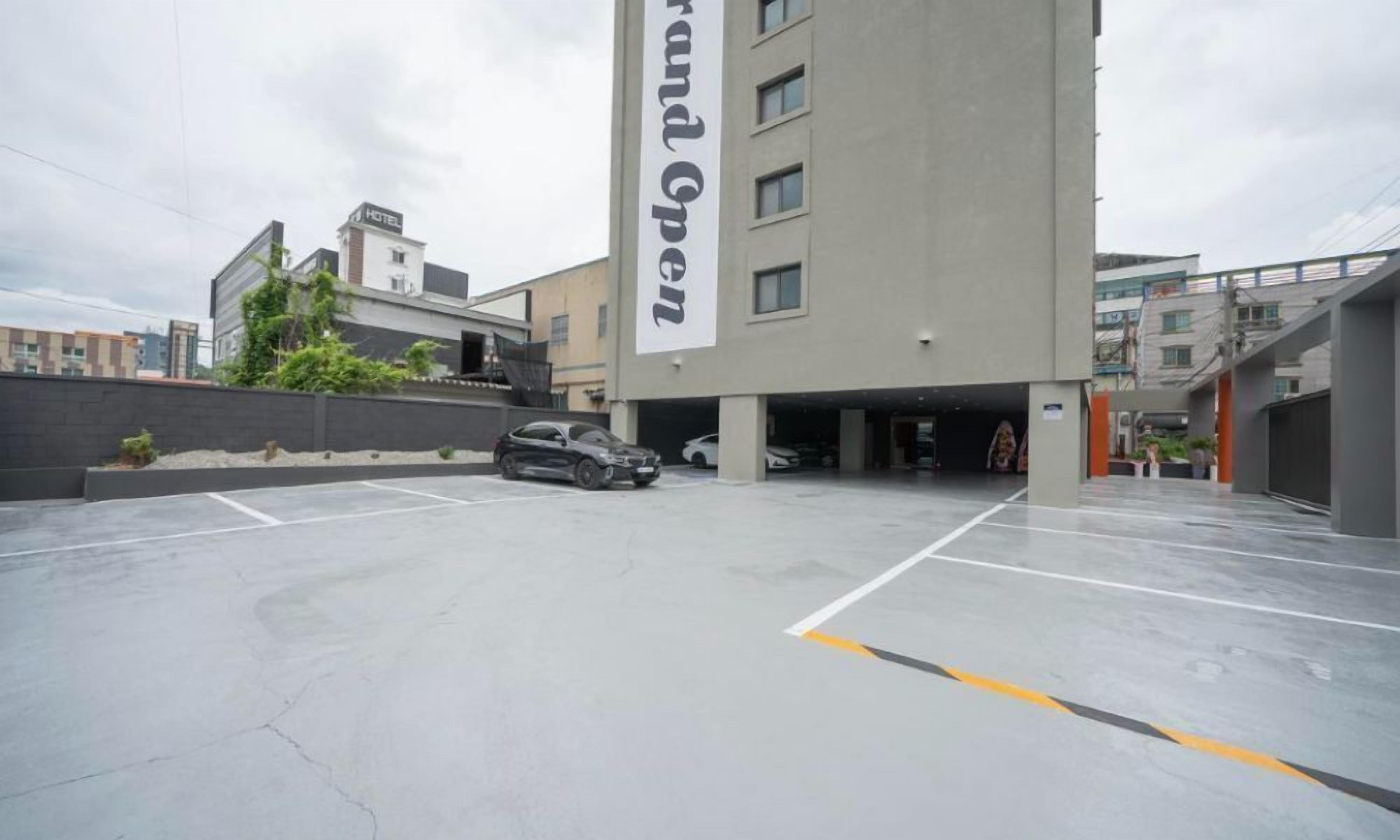Um edifício moderno de hotel com amplo estacionamento e entrada visível.