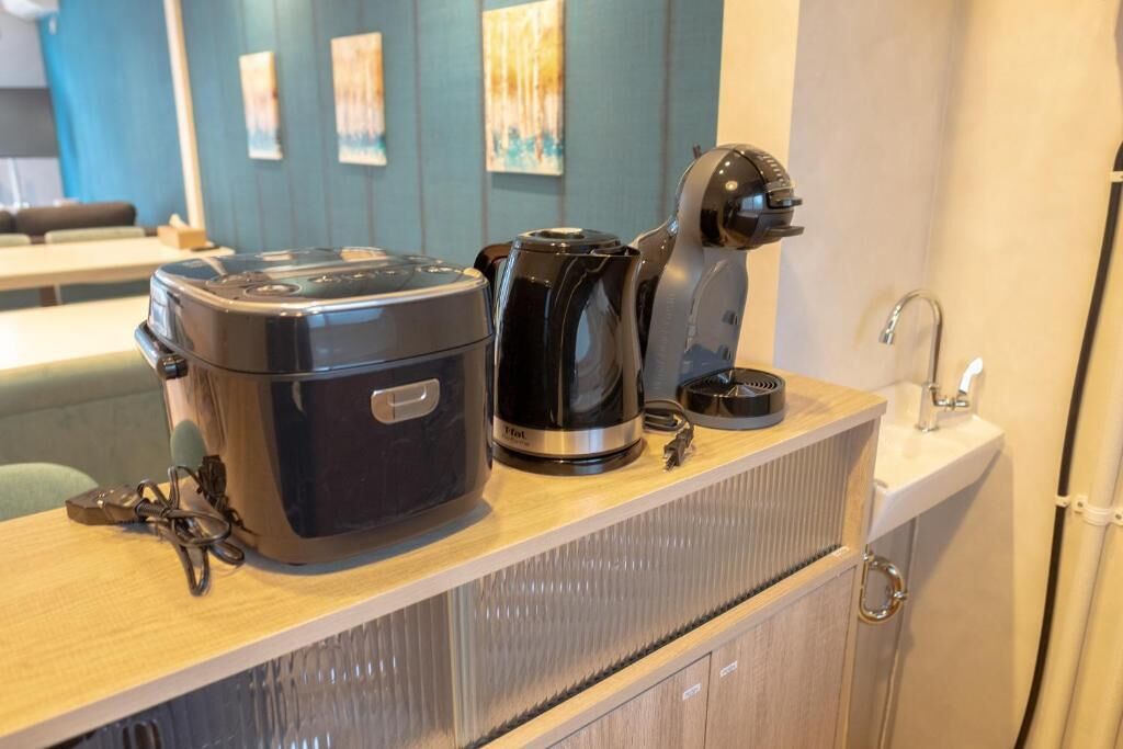 Uma bancada de cozinha com uma cafeteira, uma chaleira e uma torradeira.