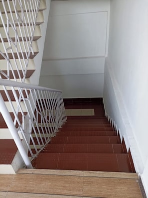 Uma escadaria com guarda-corpos brancos e degraus castanhos.