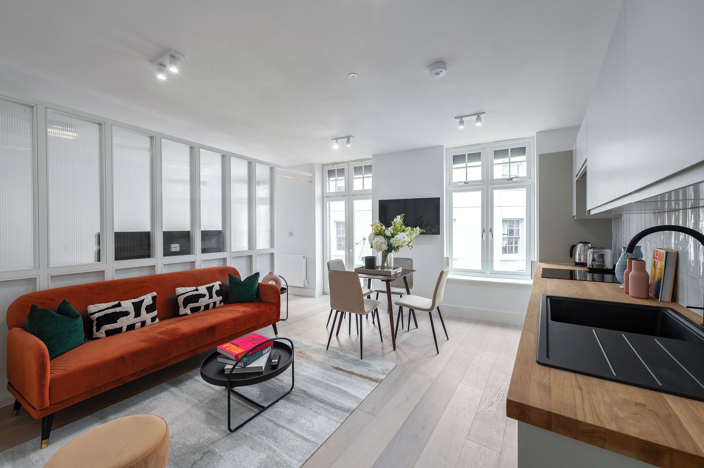 Uma sala de estar moderna com sofá, mesa de centro e área de jantar.