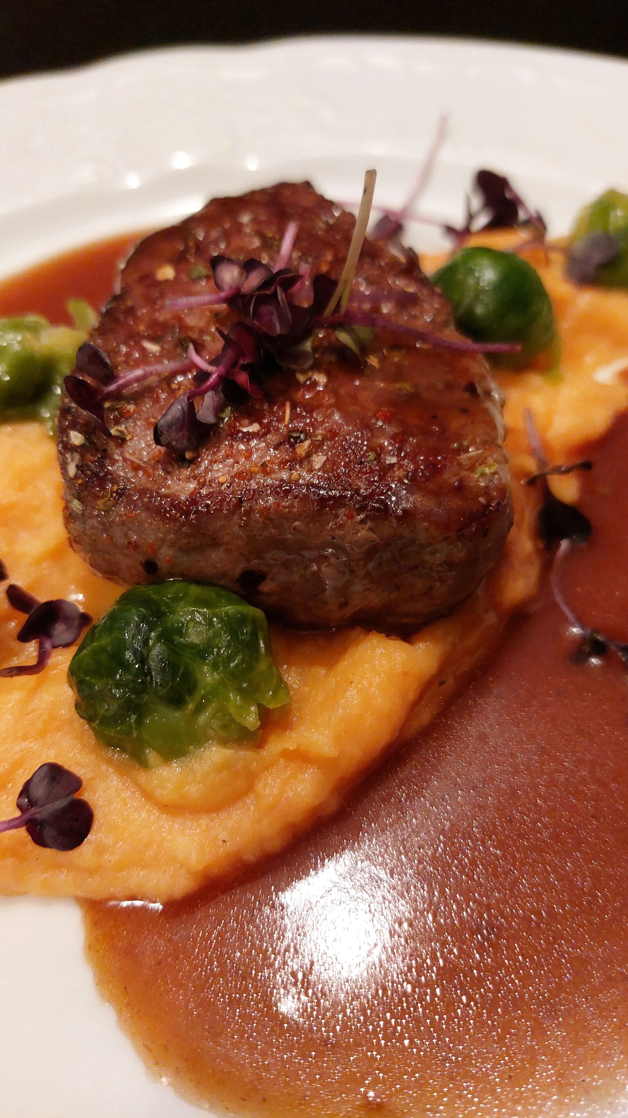 Um prato com hambúrguer, vegetais e molho.