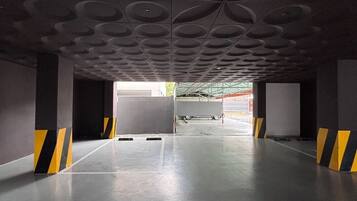 Garagem de estacionamento vazia com design moderno no teto e barreiras listradas em amarelo e preto.