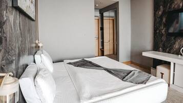 Quarto moderno com uma cama grande, mesa de cabeceira, escrivaninha e espelho.