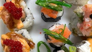 Diversos tipos de sushi com coberturas como salmão, caviar e cebolinha.