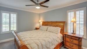 Quarto com cama de madeira, ventilador de teto e duas luminárias de cabeceira.