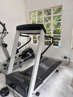 Uma academia com esteira, elíptico e bicicleta ergométrica.