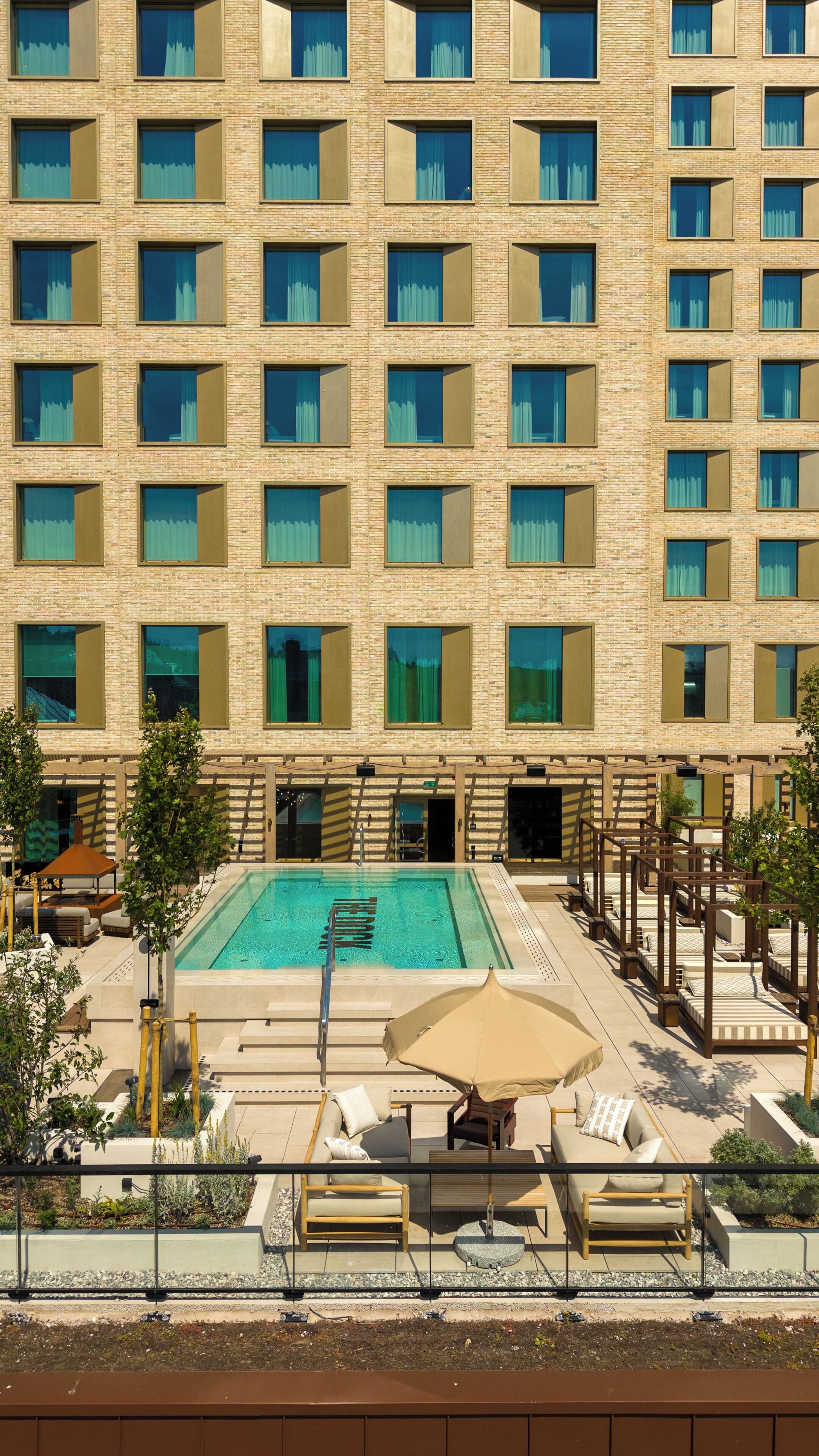 Um hotel com piscina, área de estar externa e fachada de tijolos.
