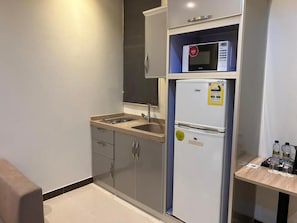 Uma cozinha compacta com micro-ondas, geladeira e pia.
